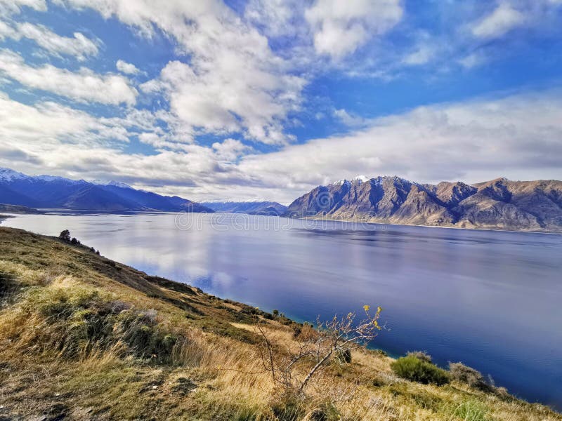 An Image of Lake Hawea with Blue Sky and Mountains on the Background ...
