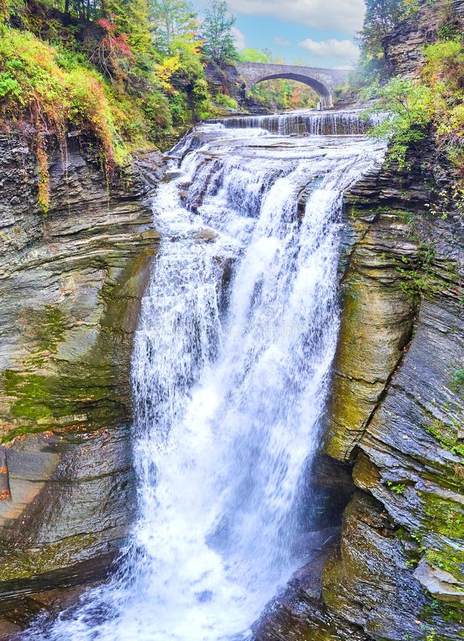 Large Waterfall into Canyon with Stone Arch Bridge in Background Stock ...