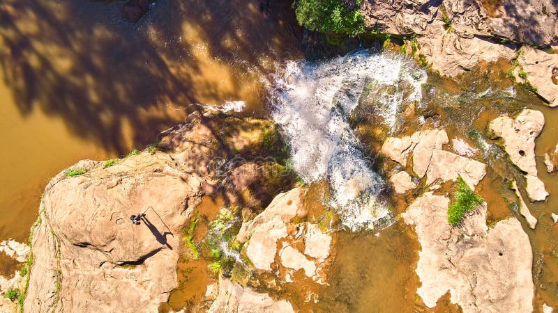 Looking Straight Down at Brown River with Large Waterfall and Hiker ...