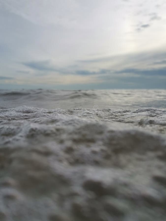 Low Angle Shot from the Beach Towards the Incoming Sea Tide at Evening ...