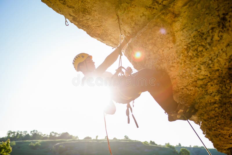 Image of Man Climber in Helmet Clambering Up Cliff. Stock Photo - Image ...