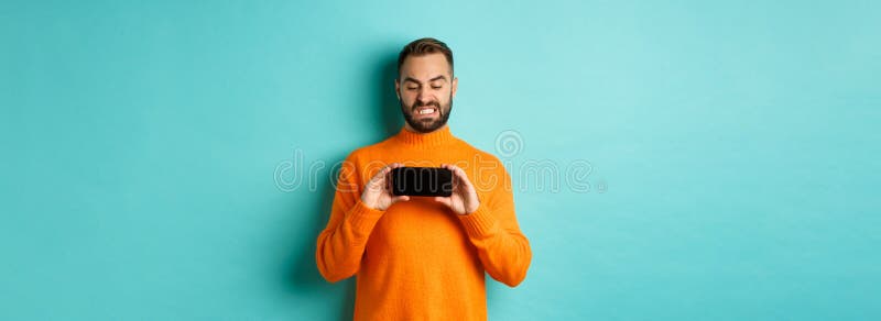 Image of Man Cringe at Something on Mobile Screen, Staring Disgusted at ...