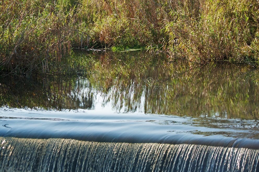 SMOOTH MIRROR LIKE WATER SURFACE BREAKING OVER a WEIR WALL Stock Image ...