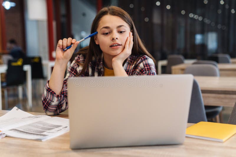 Image of Serious Girl Doing Homework with Laptop and Exercise Books ...