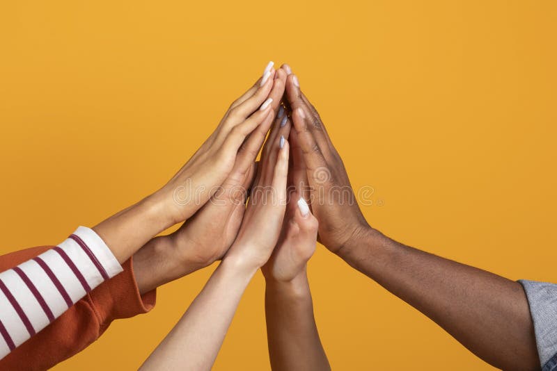 Diverse Hands Joined Together in Unity Against Yellow Background ...