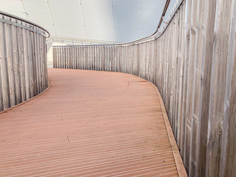 The Image Shows a Curved, Elevated Wooden Walkway with Metal Railing ...
