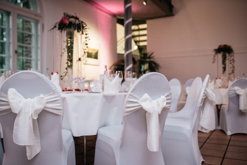 An Event Venue With White Chairs And Decorated Tables Set Up For A