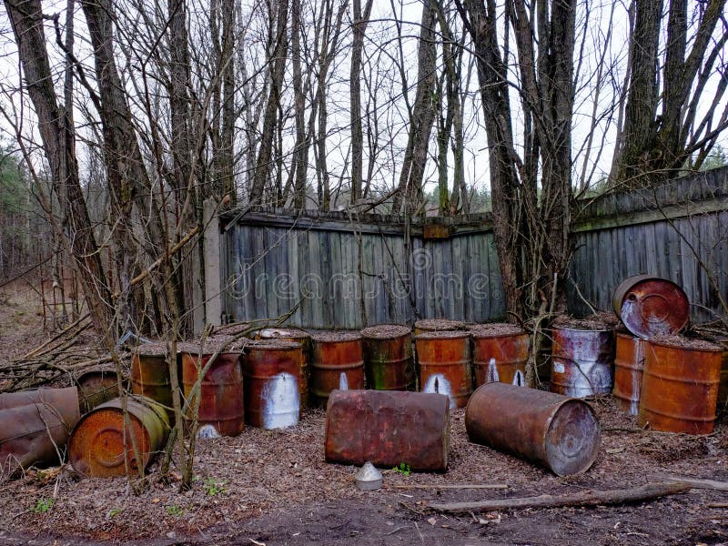 This Image Shows Rusty Barrels that are Scattered in Front of a Wooden ...