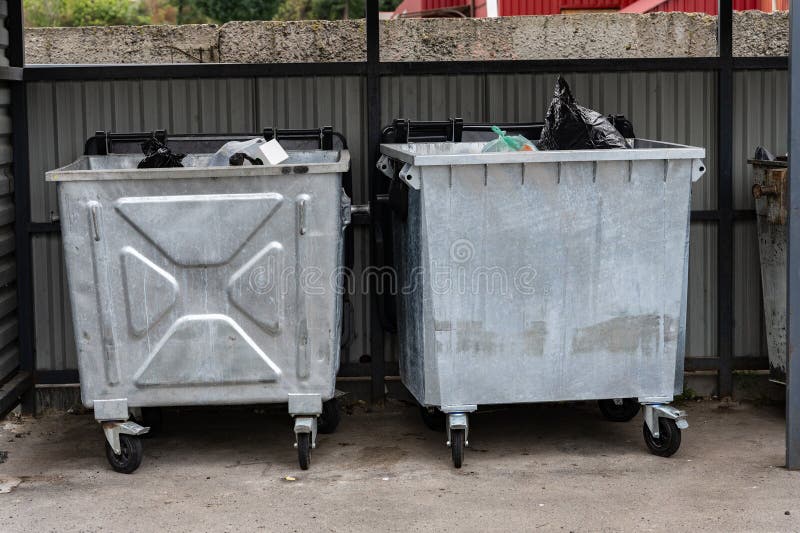 The Image Shows Two Metal Garbage Containers Lined Up Together, Filled ...