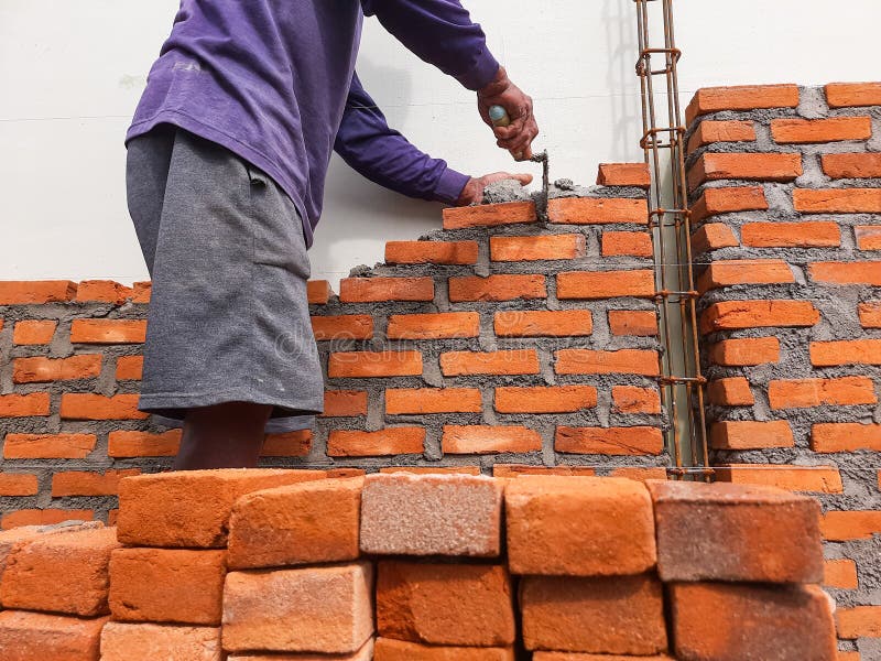 A Builder is Working on Arranging Bricks with Cement To Make a Wall ...