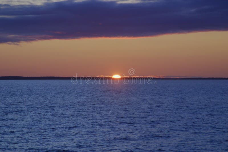 Image of the Sun Setting in the Sea Behind the Island Stock Photo ...