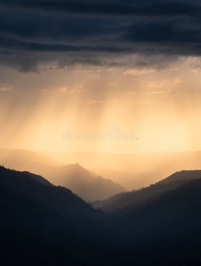An Image of Sunset in the Mountains with Dark Clouds and Light Coming ...