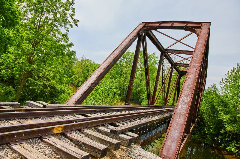 Tilted View of Rusty Iron Railroad Bridge Over River Leading into Lush ...