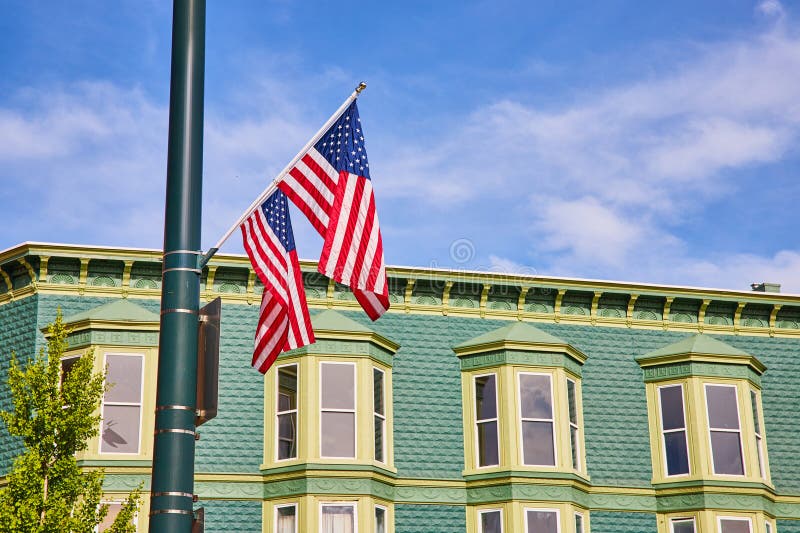 Two American Flags on Pole with Blue Sky and a Green Tree in Front of ...
