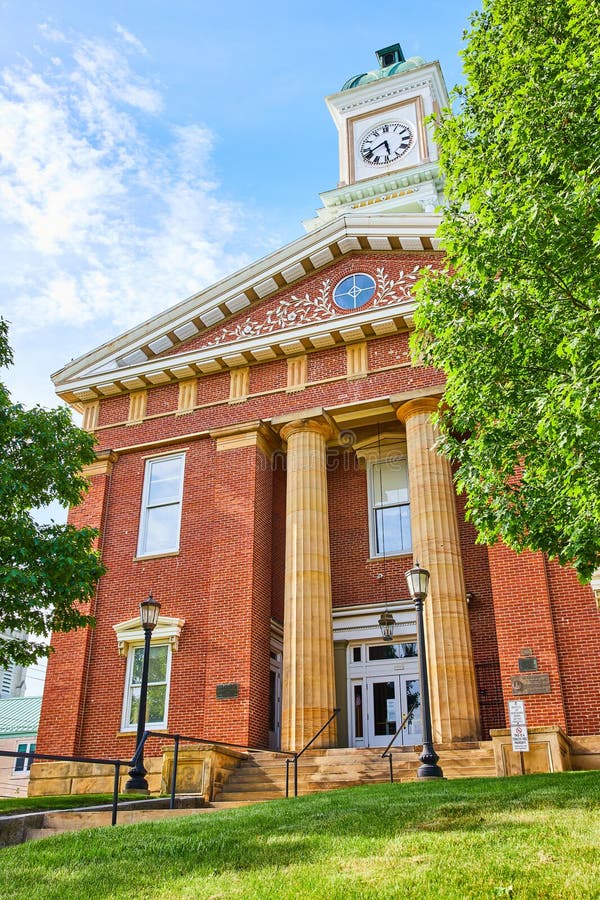 Vertical Red Brick Courthouse with Clock Tower with Blue Sky and Green ...