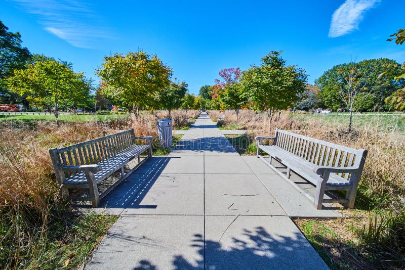 Walkway Lined with Seating Benches and Fall Grasses Against Blue Sky ...