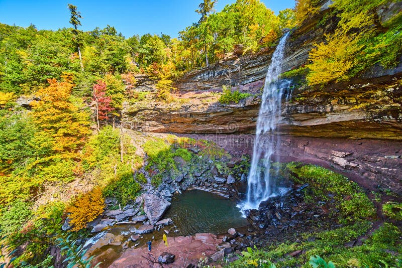 Waterfall Pours Over Layered Cliffs Surrounded by Fall Forests from ...