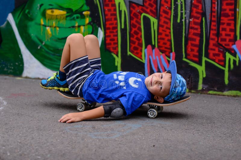 Impish Young Boy Relaxing on His Skateboard Stock Image - Image of ...