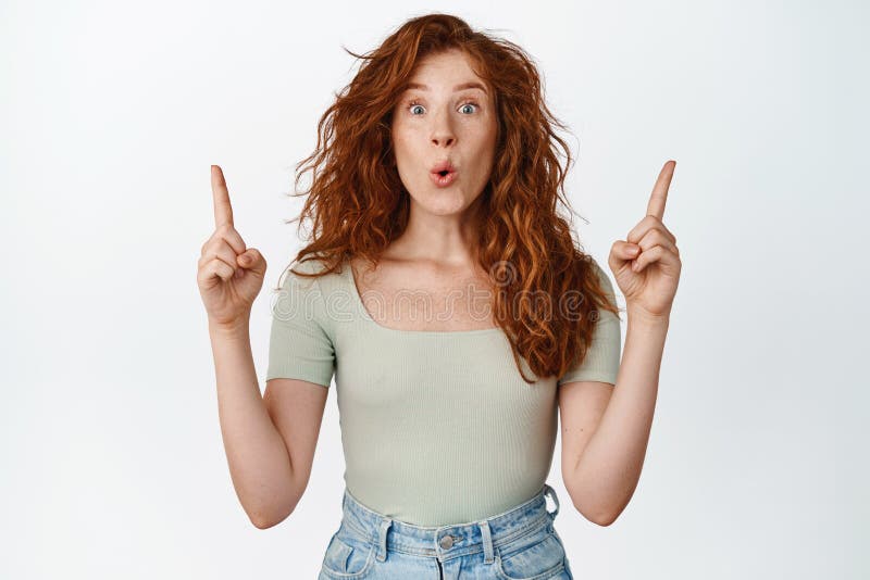 Impressed Teen Ginger Girl Looking Surprised Pointing Fingers Up