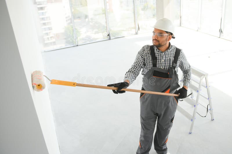 An Indian Apartment Repair Worker Paints a White Wall with a Roller ...