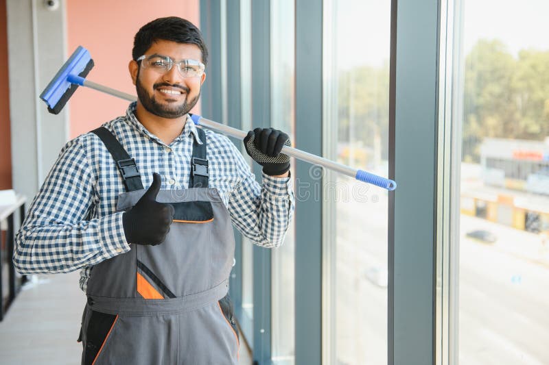 An Indian Cleaning Service Worker Washes Windows in an Office Building ...