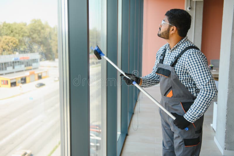 An Indian Cleaning Service Worker Washes Windows in an Office Building ...