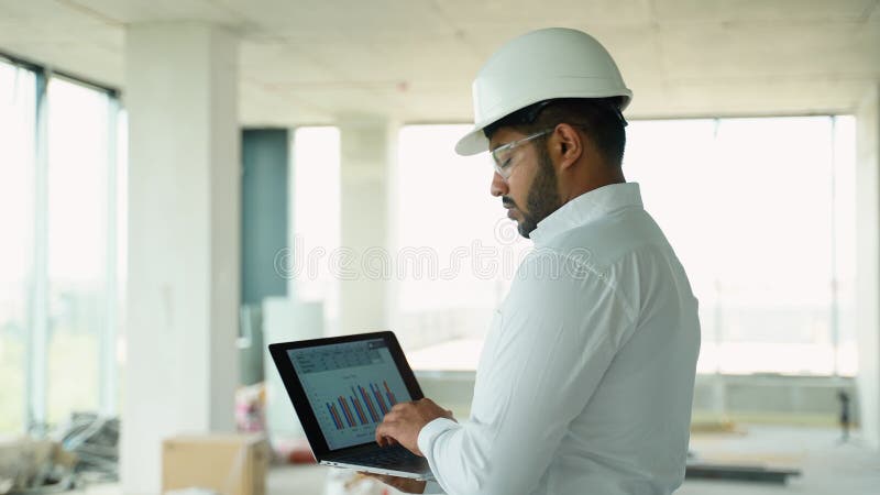 Indian Engineer Analyzing Construction Project Data on-site Using ...
