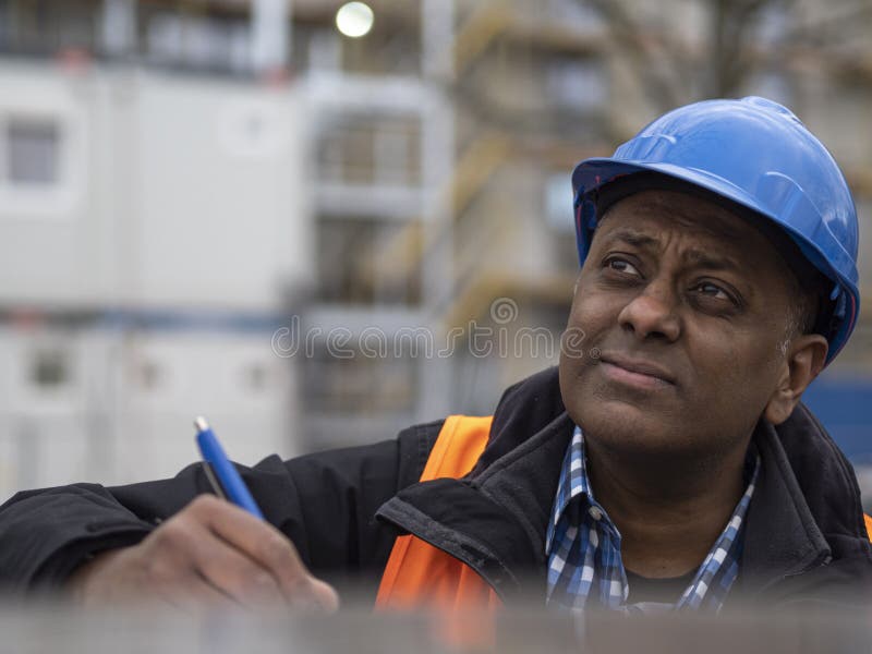 Frowning Engineer Putting on His Safety Helmet and Looking Aside ...