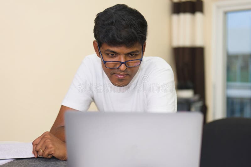 Indian Male Student Studying at Home Using Laptop Computer and Writing ...