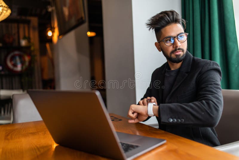 Young Indian Man Look at Watch while Working on Laptop on Cafe Stock ...