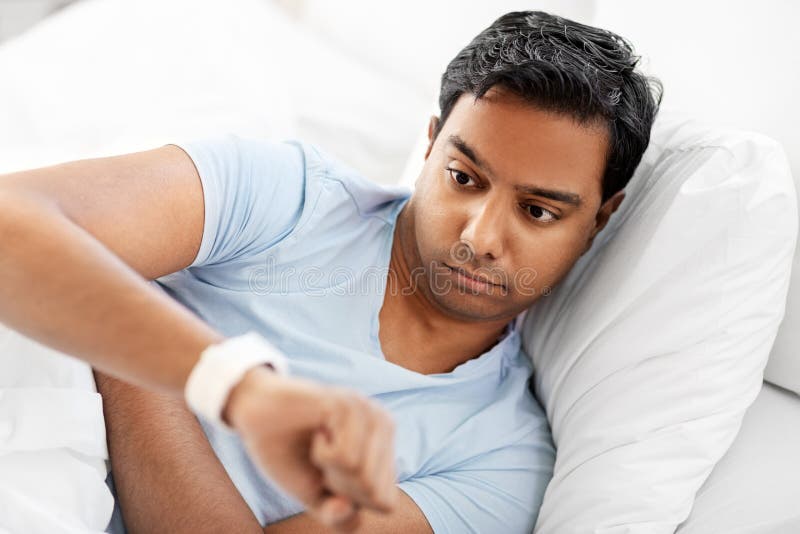 Indian Man Looking at Smart Watch in Bed at Home Stock Image - Image of ...