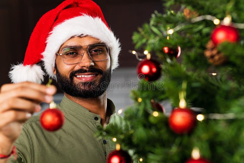 Indian Man in Santa Hat Decorating Christmas Tree with Baubles Stock ...