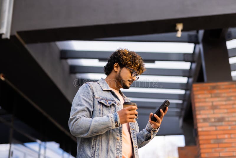 Indian Young Man Use Phone Drinking Phone while Walking on the Street ...