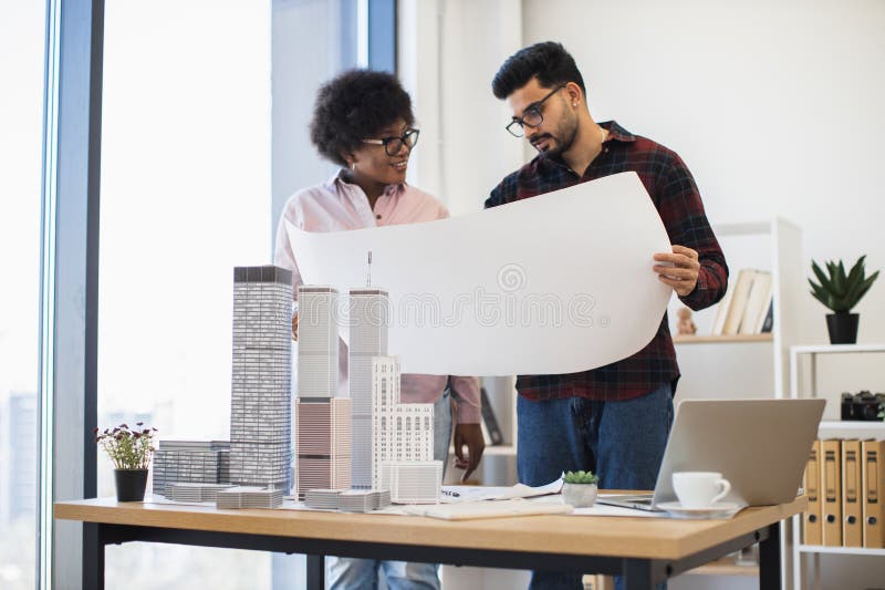 Architects Reviewing Blueprints for a Modern City Project in Office ...