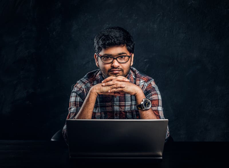 Indian Programmer Sits at a Desk with a Laptop and Look at the Camera ...