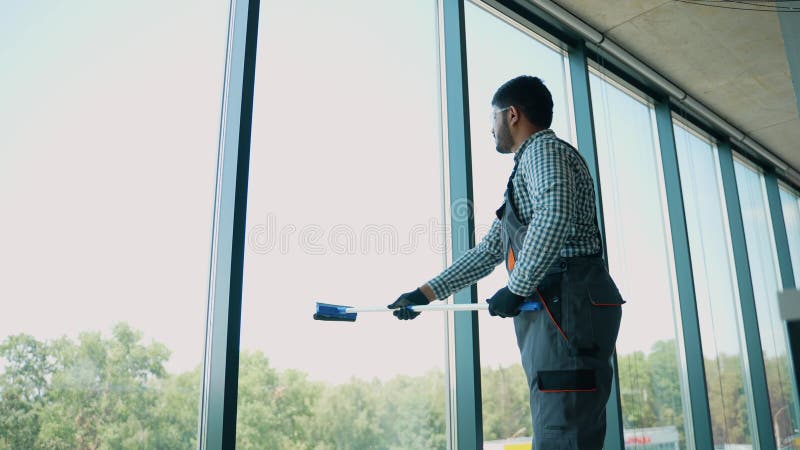 Indian Worker from a Cleaning Service Cleans Large Office Windows Using ...