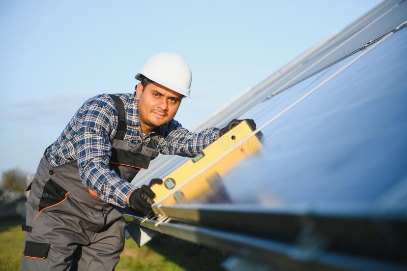 An Indian Worker in Uniform and with Tools Works on a Solar Panel Farm ...