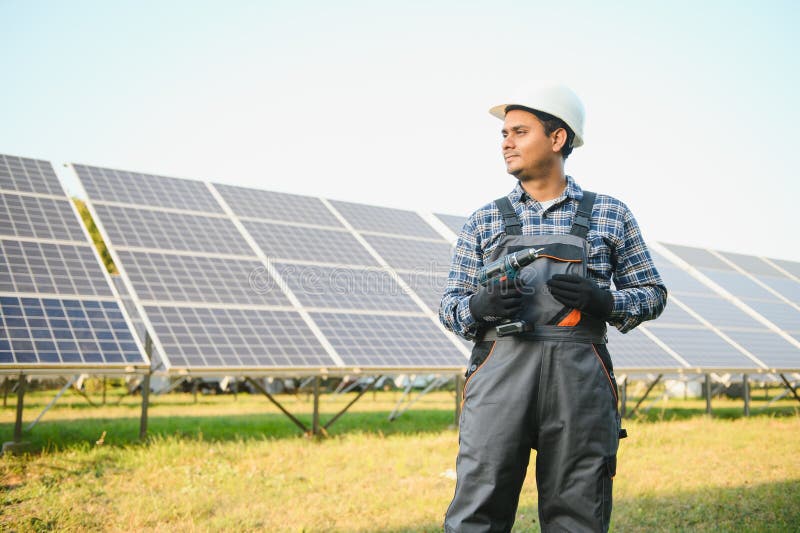 An Indian Worker in Uniform and with Tools Works on a Solar Panel Farm ...