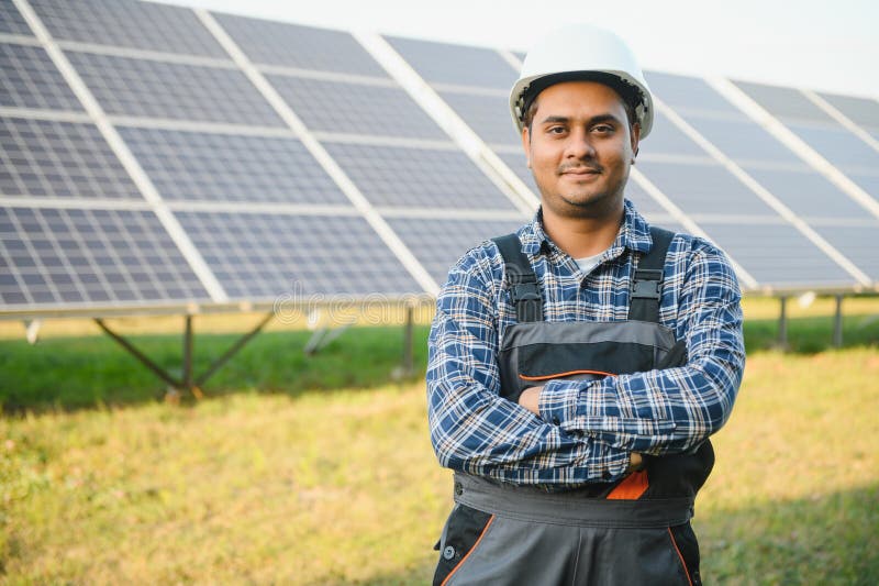 An Indian Worker in Uniform and with Tools Works on a Solar Panel Farm ...