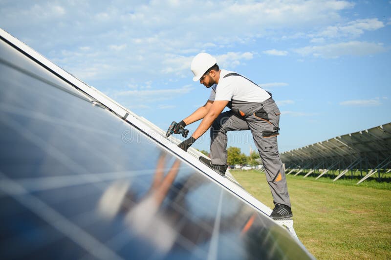 An Indian Worker in Uniform and with Tools Works on a Solar Panel Farm ...