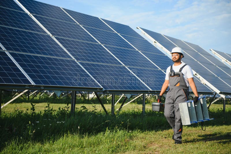 An Indian Worker in Uniform and with Tools Works on a Solar Panel Farm ...