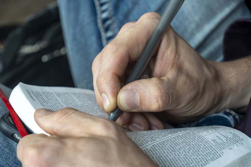 An Individual is Engaged in Writing on a Book Using a Pen To Do so ...