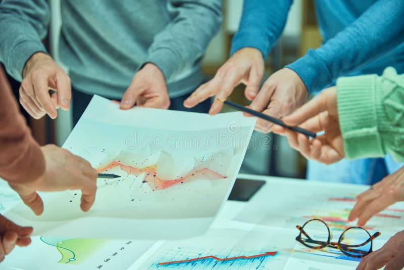 Individuals Examining and Discussing a Complex Data Visualization Sheet ...
