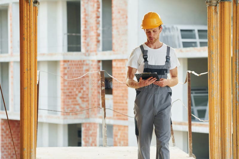 Indoors in the Room. Young Man Working in Uniform at Construction at ...