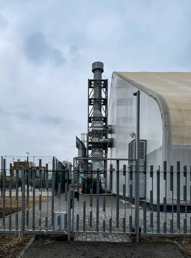 Industrial Building with Metal Chimney and Fenced Perimeter, Showcasing ...