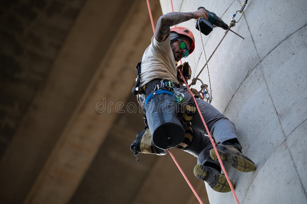 Industrial Climber Using Cordless Drill on Concrete Wall Under Bridge ...