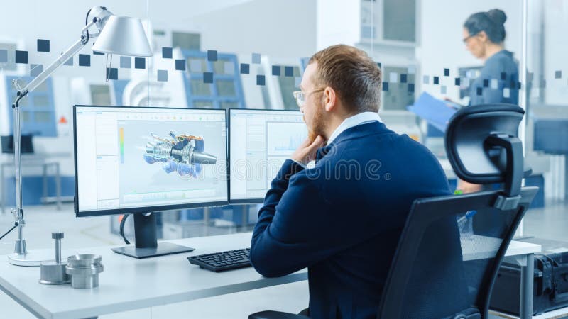 Industrial Engineer Working on a Personal Computer, Two Monitor Screens ...