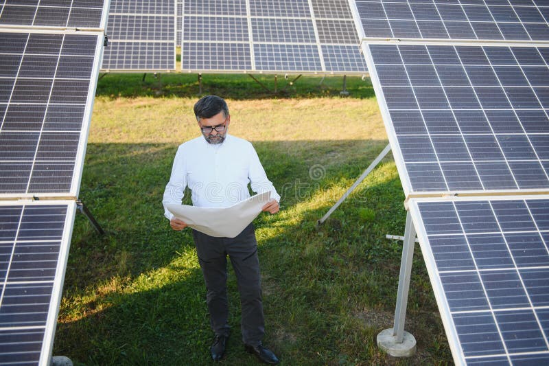 Industrial Senior Man Engineer Walking through Solar Panel Field for ... Industrial Senior Man Engineer Walking through Solar Panel Field for ...
