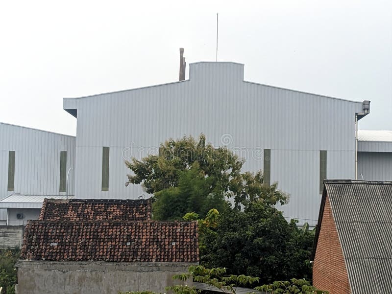 Industrial Warehouse Behind Traditional Rooftops and Trees Stock Photo ...