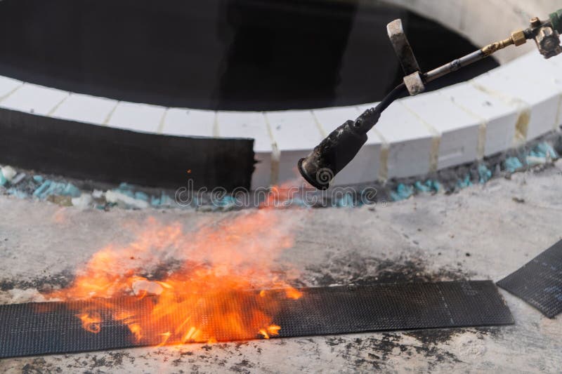 An Industrial Worker Uses Fire To Soften a Rubber Underlay for Floor ...